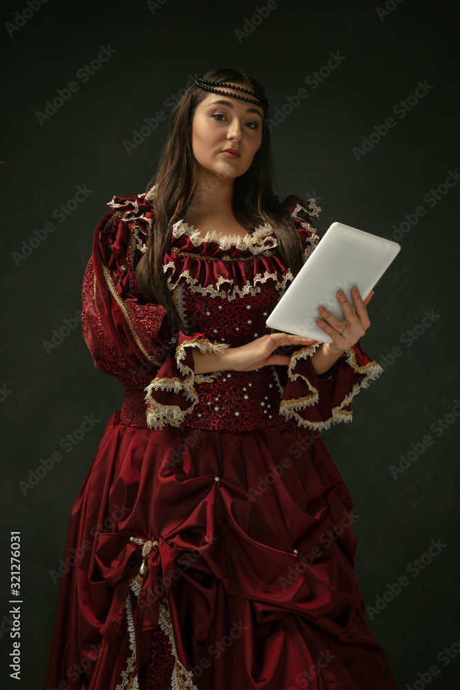 Calm. Portrait of medieval young woman in red vintage clothing using ...