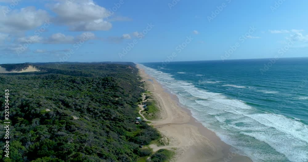 4k forward tracking aerial view of sandy coastal beach and pounding ...