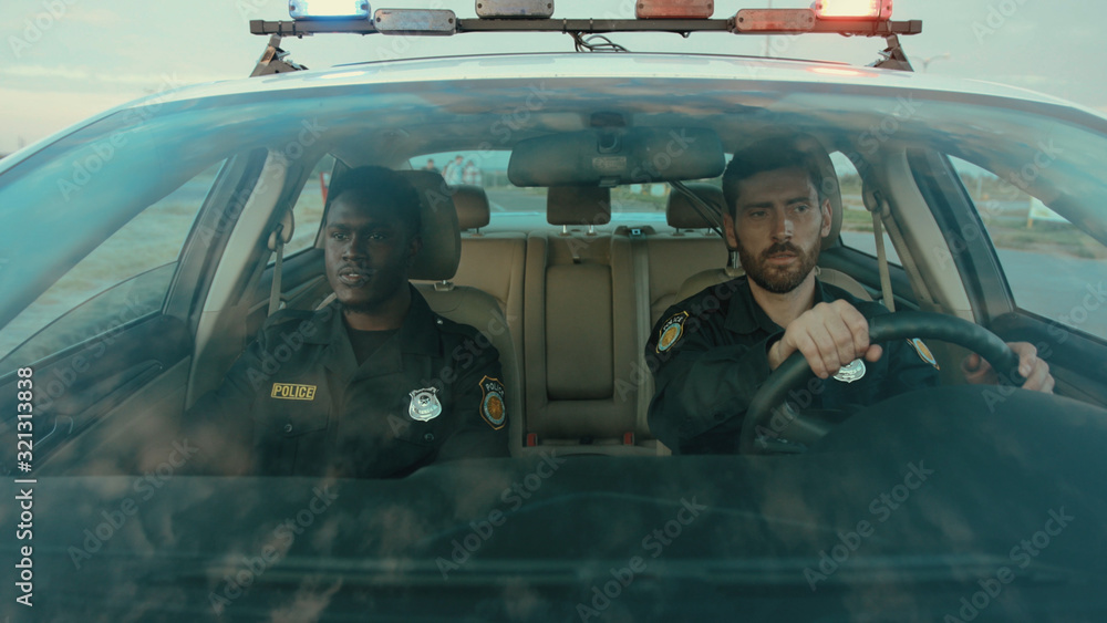 Two friendly colleagues cops driving a police car with lightbar ...