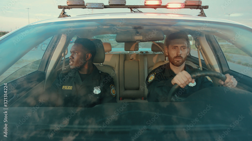 Portrait of two serious police officers driving to road accident area ...