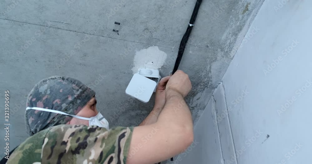 Male electrician in protective mask stretches high-voltage cable across ...