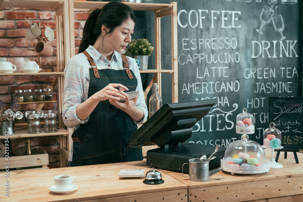 skillful female cafe worker looking at screen of pos machine. lady ...