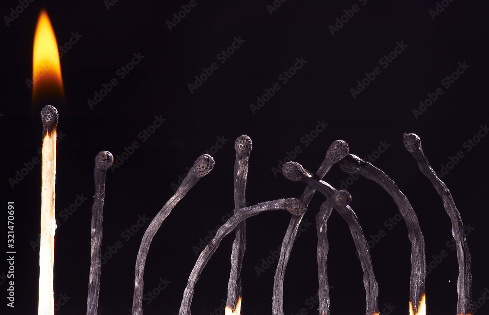 row of burned-out matches over the black background. one match is ...