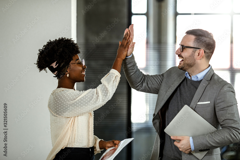 Businessman and businesswoman celebrating success by doing the high ...