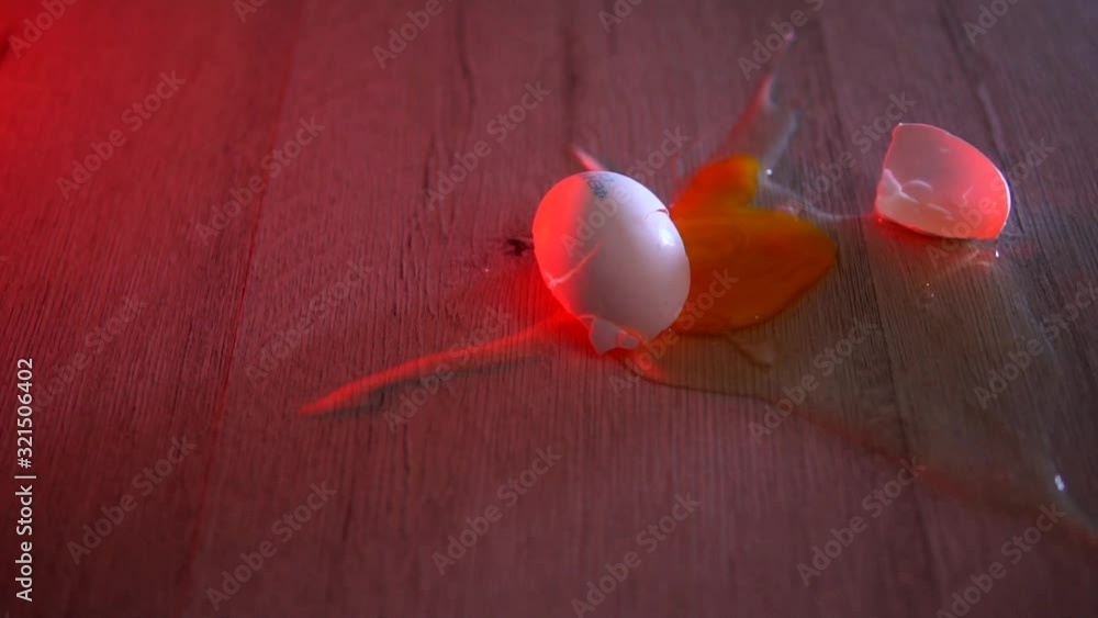 Egg fall to the floor and break. Yolk and protein slowly spread across ...