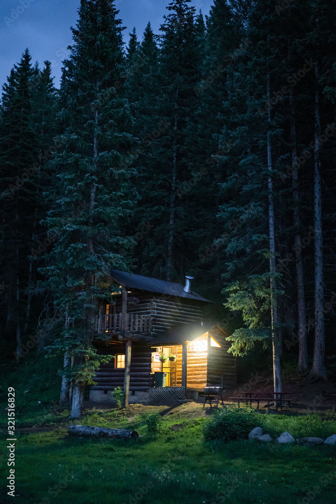 Cabin in woods at night with front porch light on Stock Photo | Adobe Stock
