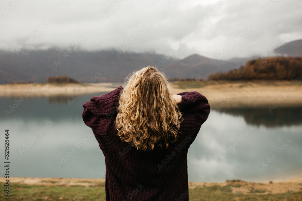 happy girl with curly blond hair dances on a lake alone, her hair is ...