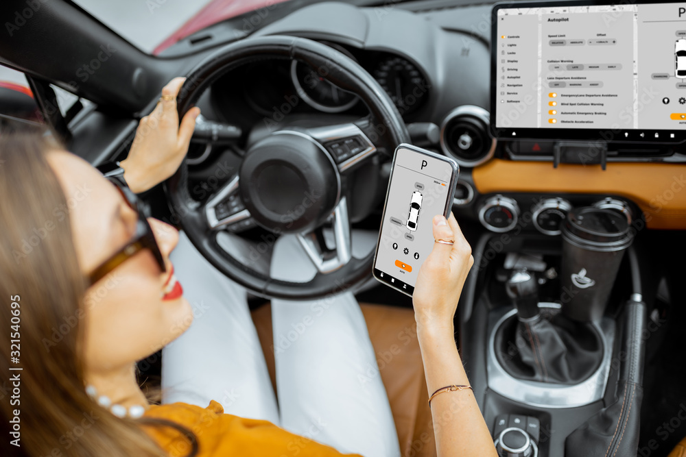 Young woman controlling car using smart phone with launched mobile ...