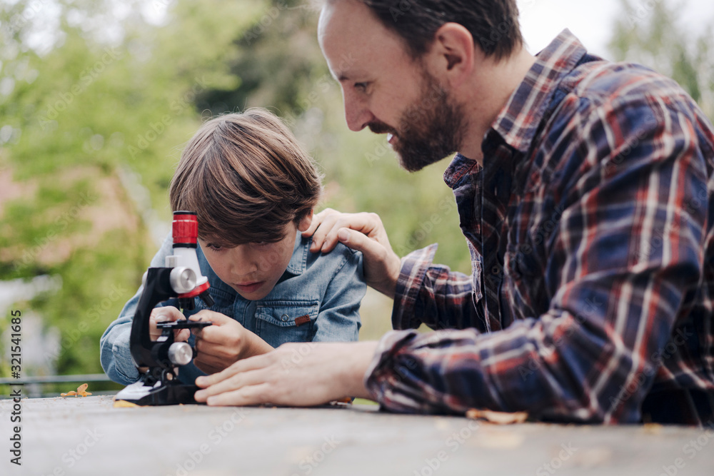 Father and son looking at objects under a microscope Stock Photo ...