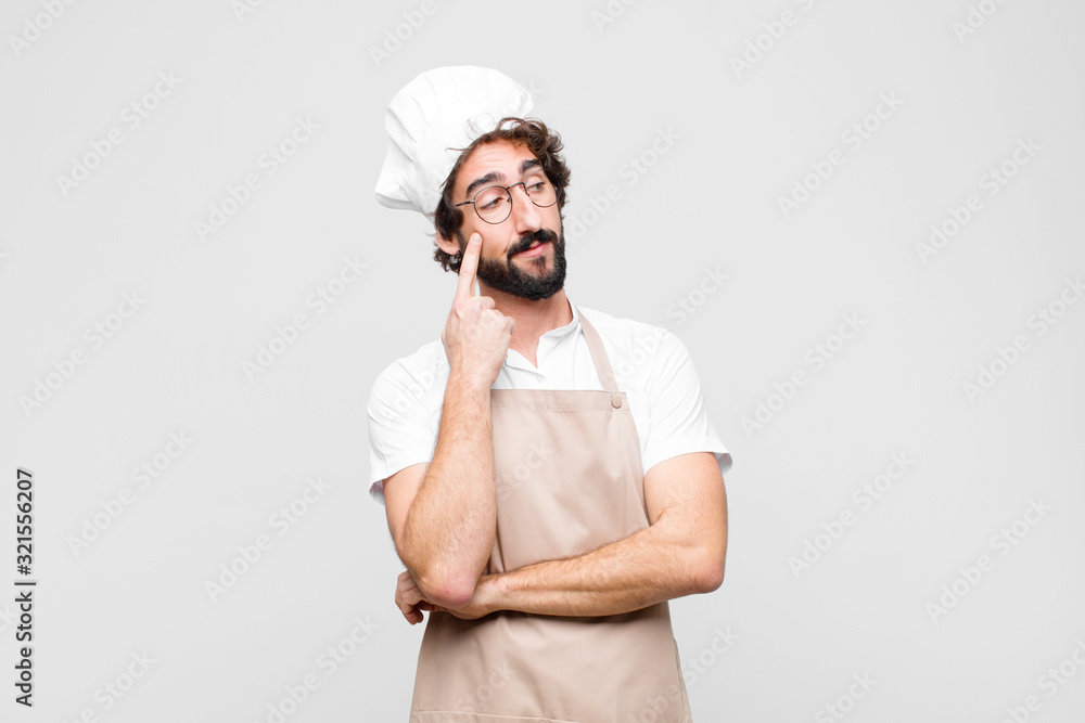 young crazy chef with a concentrated look, wondering with a doubtful ...