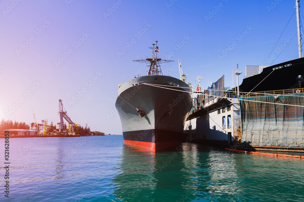 front of Military ship moored alongside near floating dock yard during ...