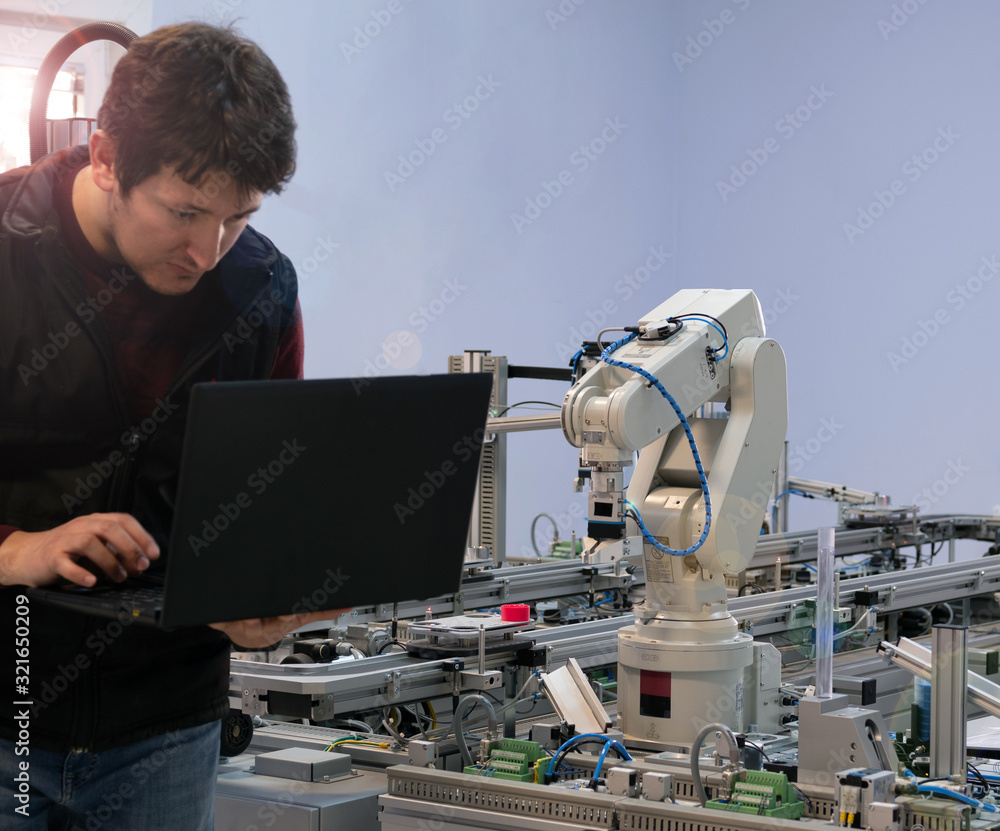 Close-up of Robot arm. Engineer is working on laptop to programming ...