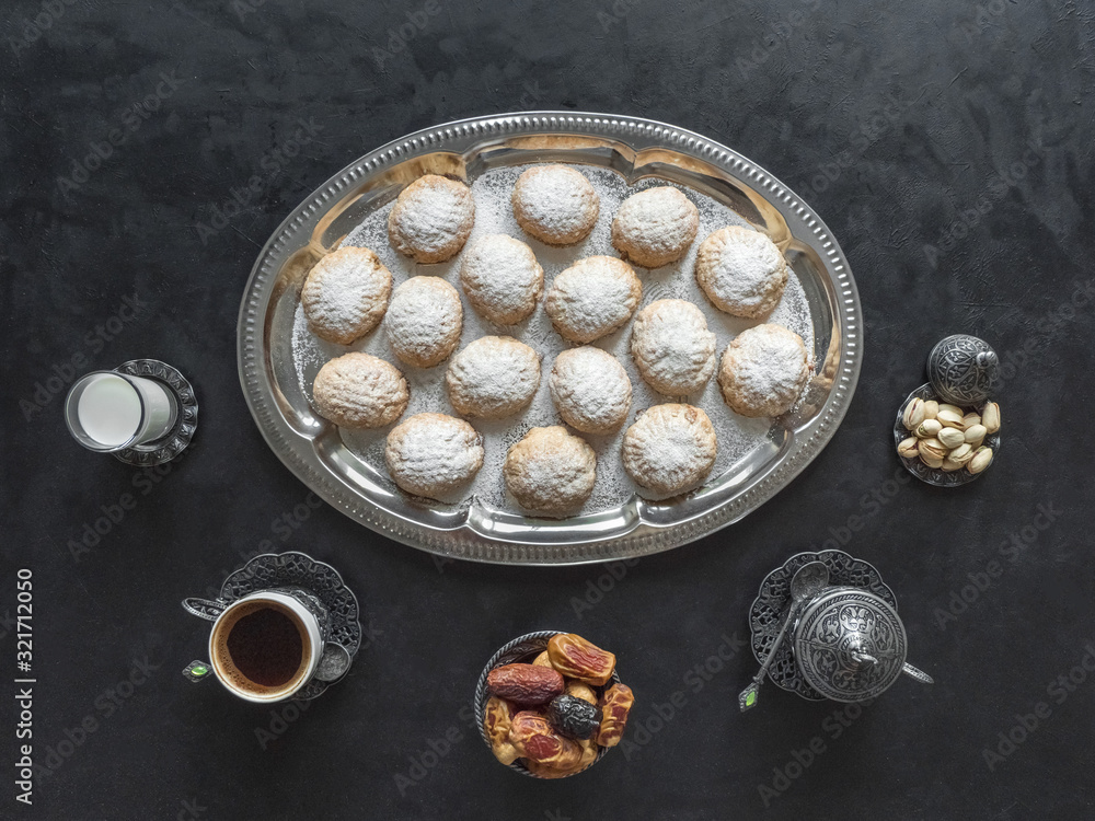 Festive Ramadan sweets are served with tea on the black table. Egyptian ...