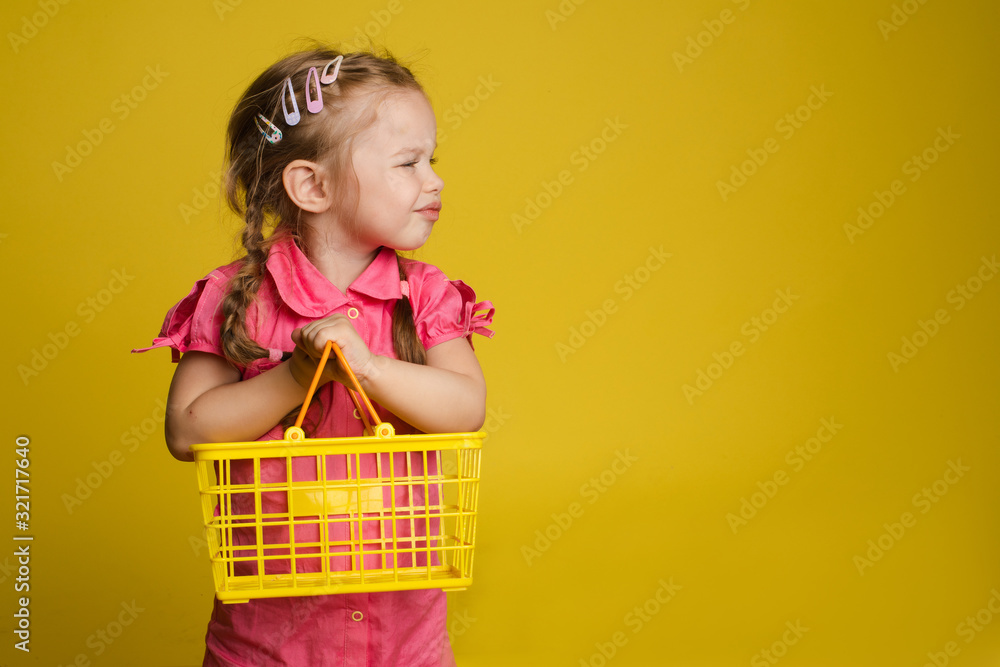 Cunning little cute girl holding small basket posing isolated at yellow ...