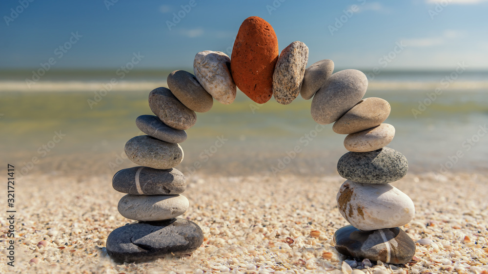 Stone arch with red stone at top in the morning on a beach. Wellness ...