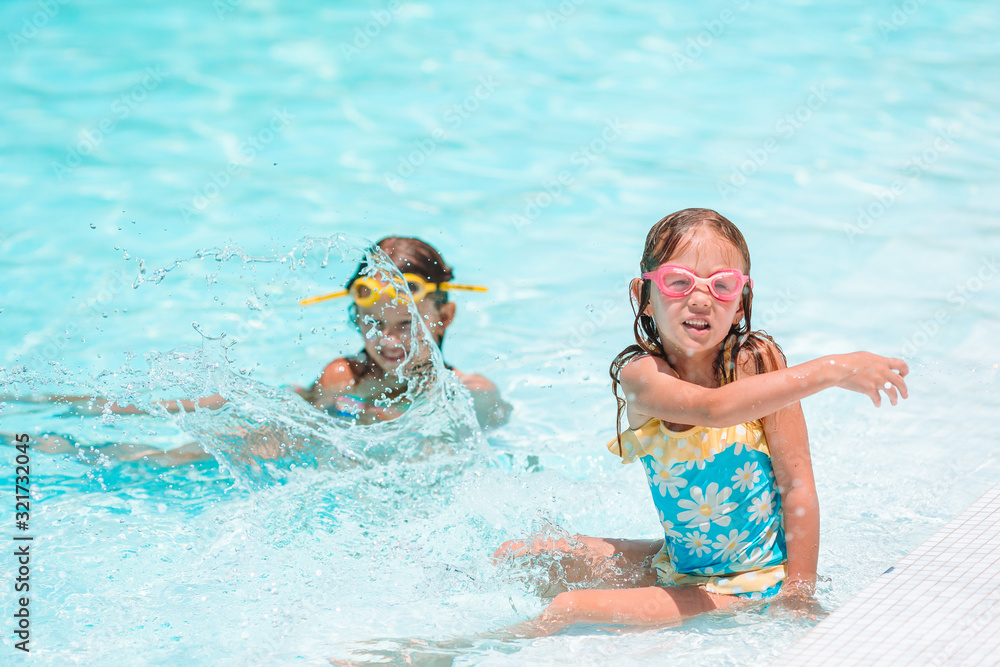 Adorable little girls playing in outdoor swimming pool on vacation ...