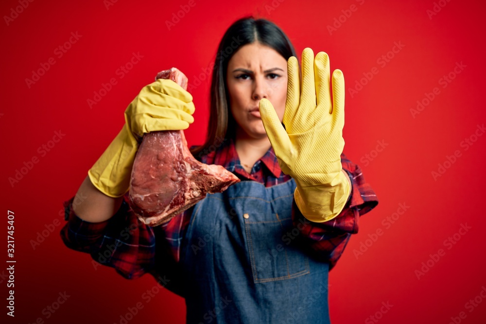 Young butcher woman holding fresh raw beef meat stake over red ...