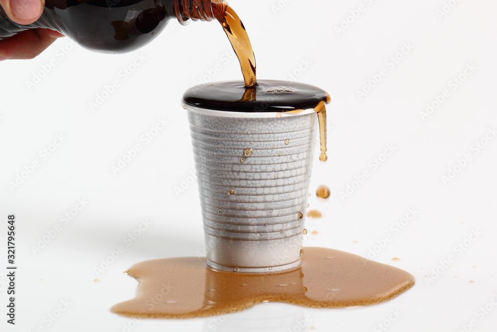 Human hand pouring cola from plastic bottle into overflowing disposable ...