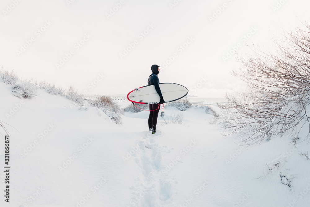Cold winter and surfer with surfboard. Snowy day with surfer in wetsuit ...