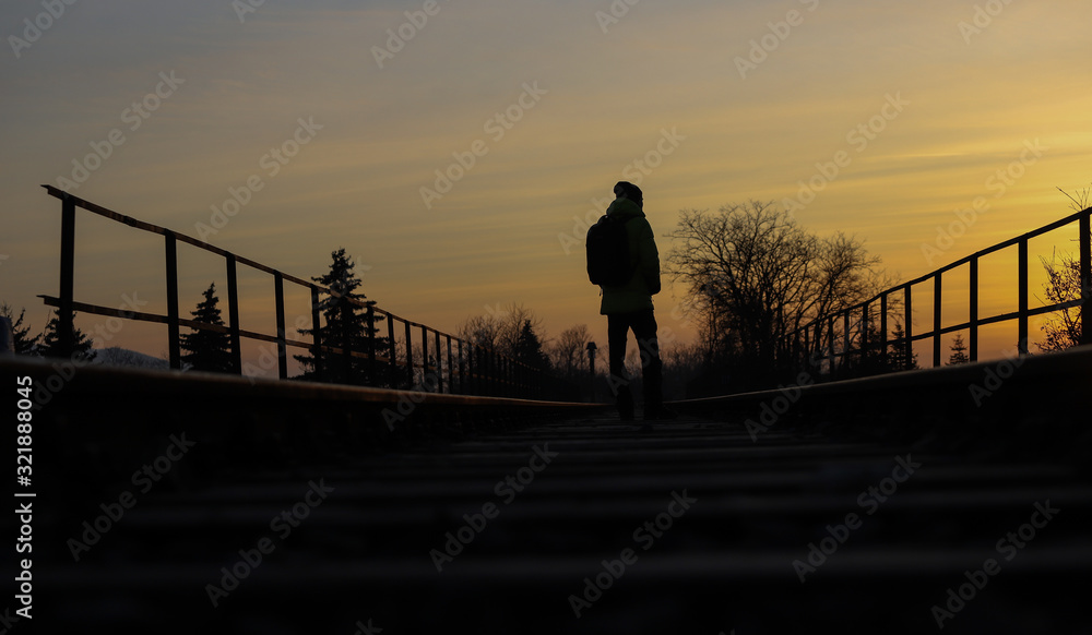 Persona parada en medio de las vías antiguas de un tren al atardecer ...