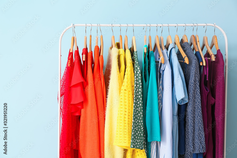Rack with modern clothes near color wall Stock Photo | Adobe Stock