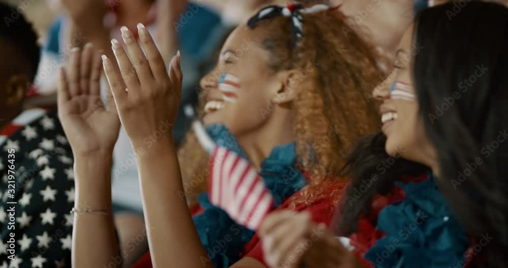 Women with USA flag sitting in stadium stands clapping and cheering for ...
