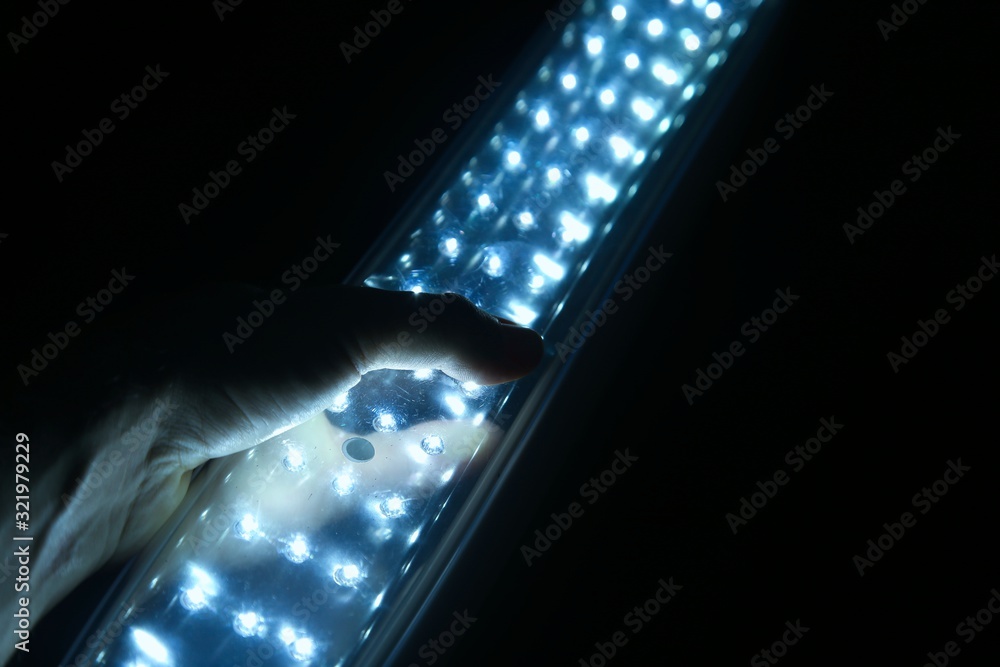 Hand holding a rechargeable LED light lantern in the dark. Load ...