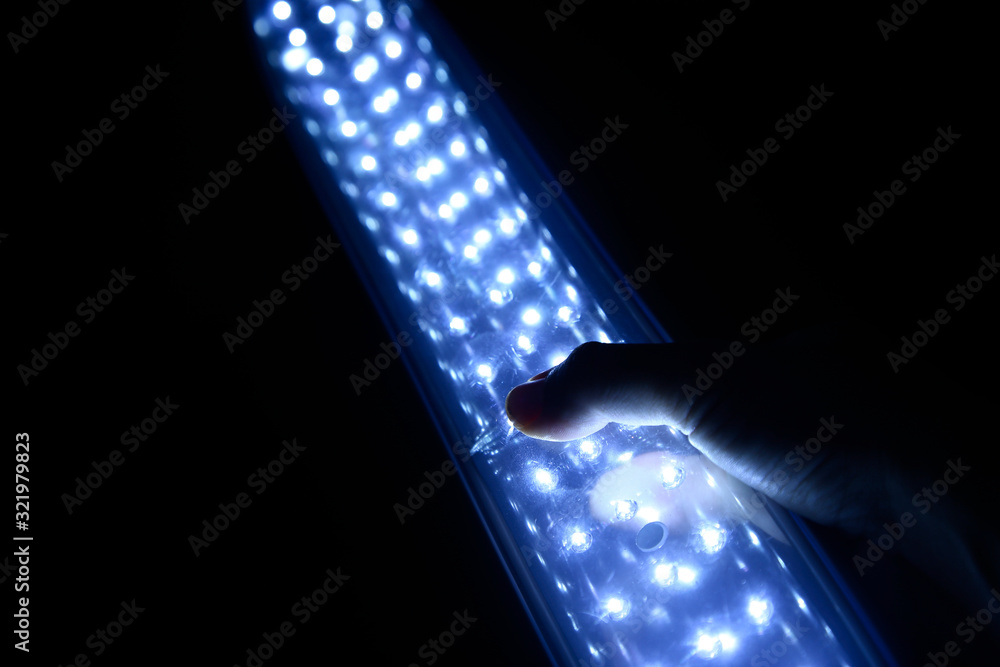 Hand holding a rechargeable LED light lantern in the dark. Load ...