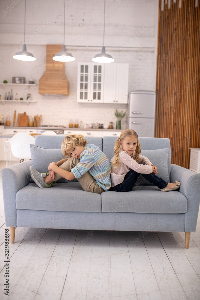 Kids sitting back to back and hugging knees Stock Photo | Adobe Stock