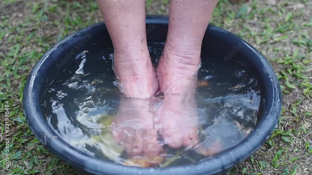 Close-up of spa foot with herbs water for relaxation treatment. Senior ...