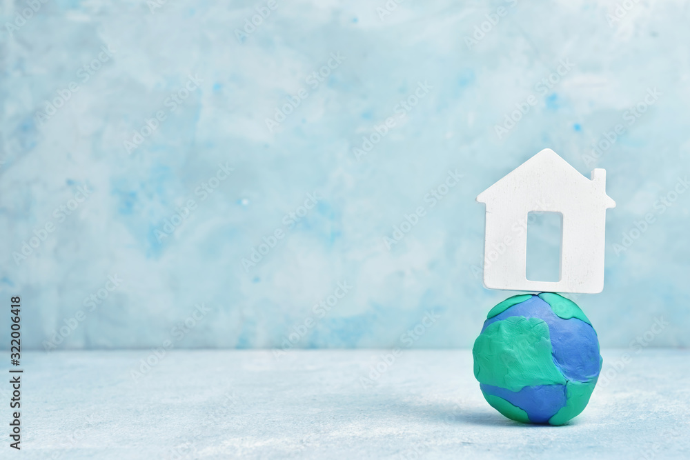 Planet and figure of house on color background. Earth Day celebration ...