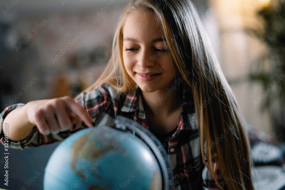 Portrait of cute little girl in living room looking globe. Pretty girl ...