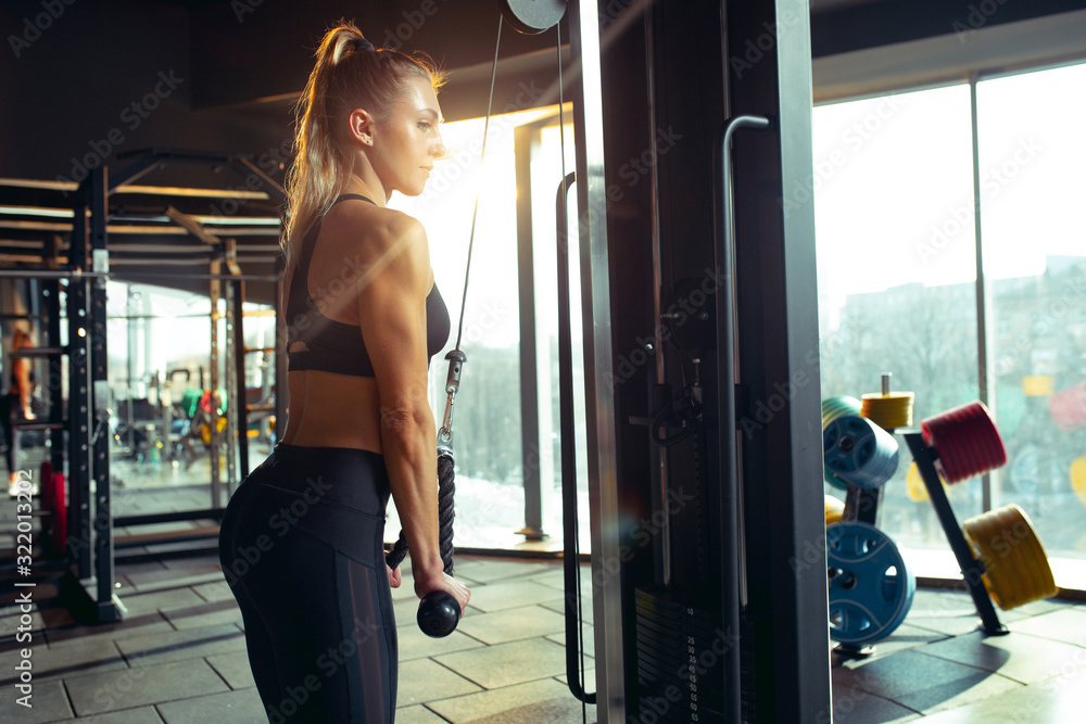Calm. Young muscular caucasian woman practicing in gym with the weights ...