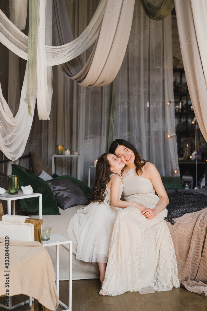 Mother and daughter hugging and cuddling in bed. Pretty little girl and ...
