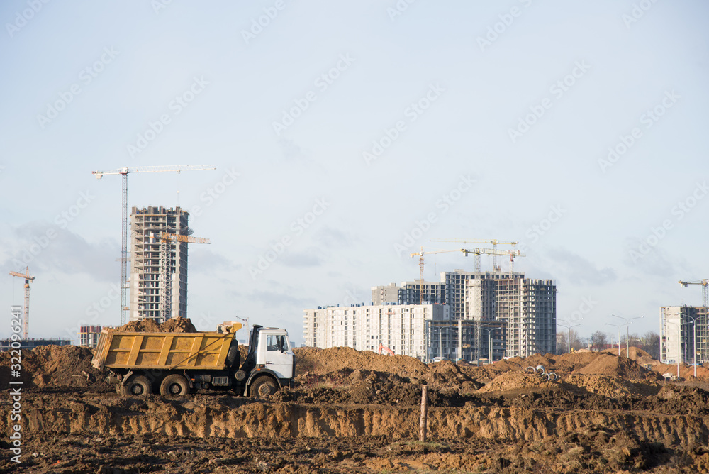 Heavy dump trucks and hydraulic luffing jib tower cranes works at a ...