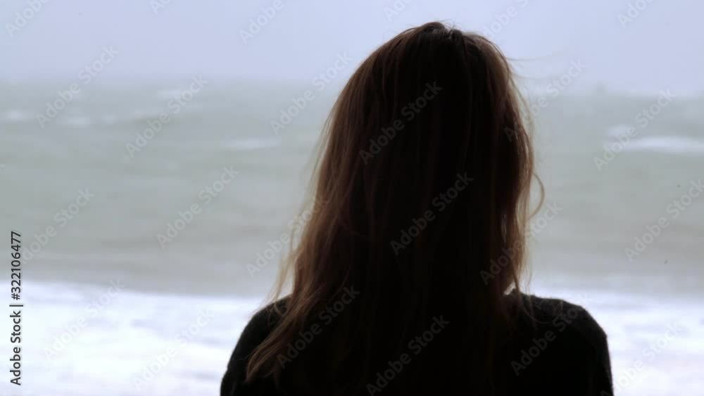 The girl looks at the raging sea. A woman is watching the storm ...