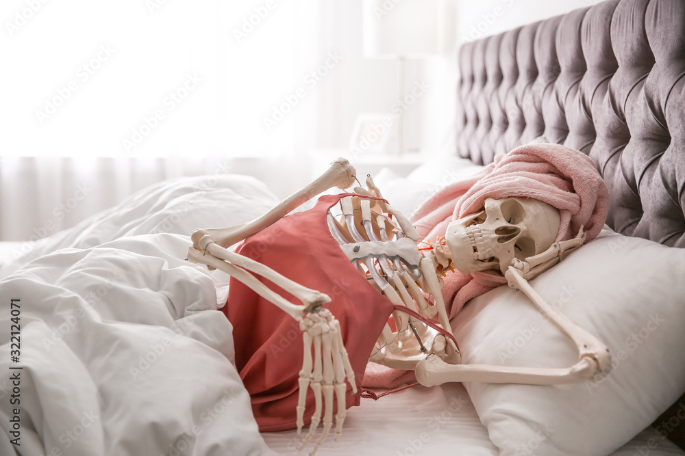 Human skeleton in silk pajamas and towel lying on bed indoors Stock ...
