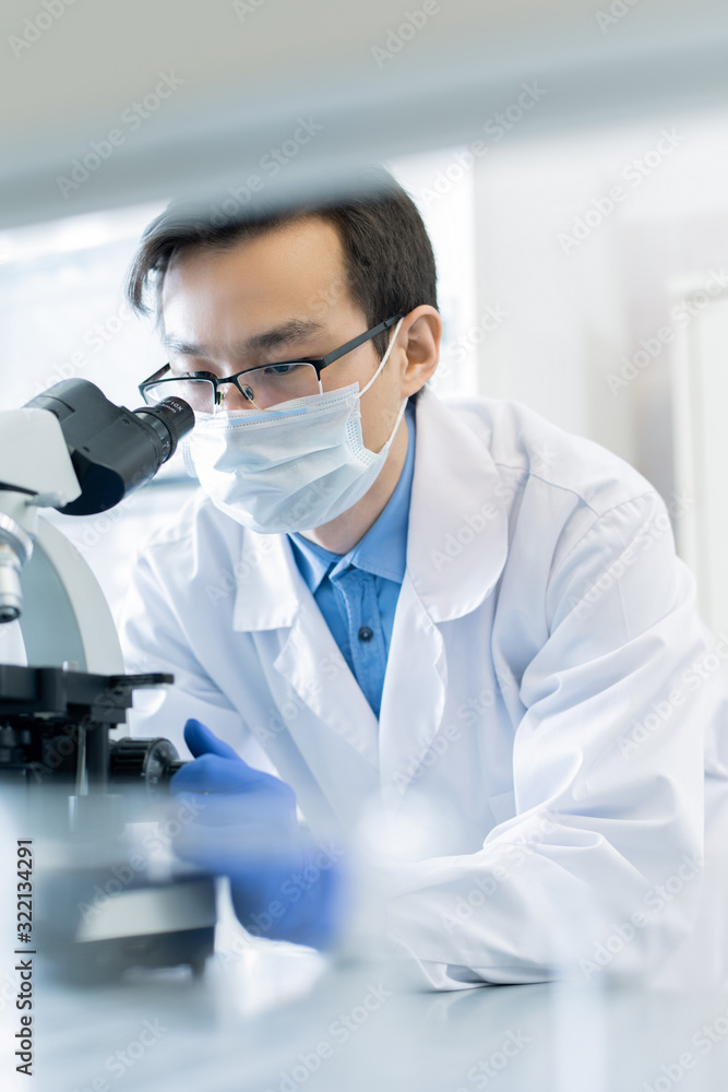 Vertical portrait of young Asian pharmacologist wearing protective mask ...