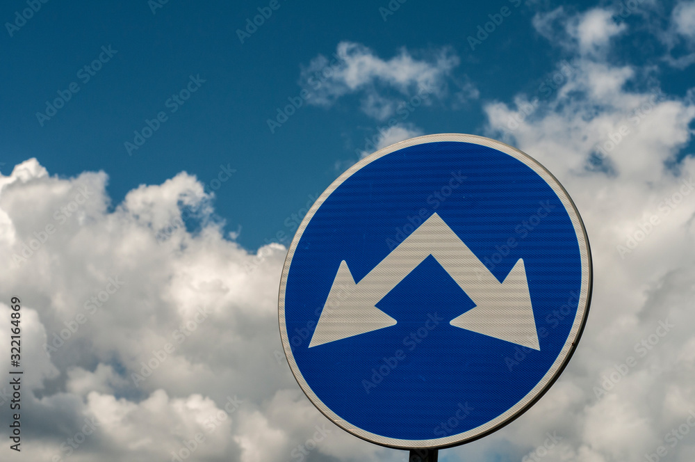 Blue traffic road sign with two arrows for two directions closeup on ...