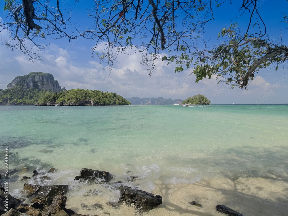 view of many arch rocks floating in blue-green sea with green island ...