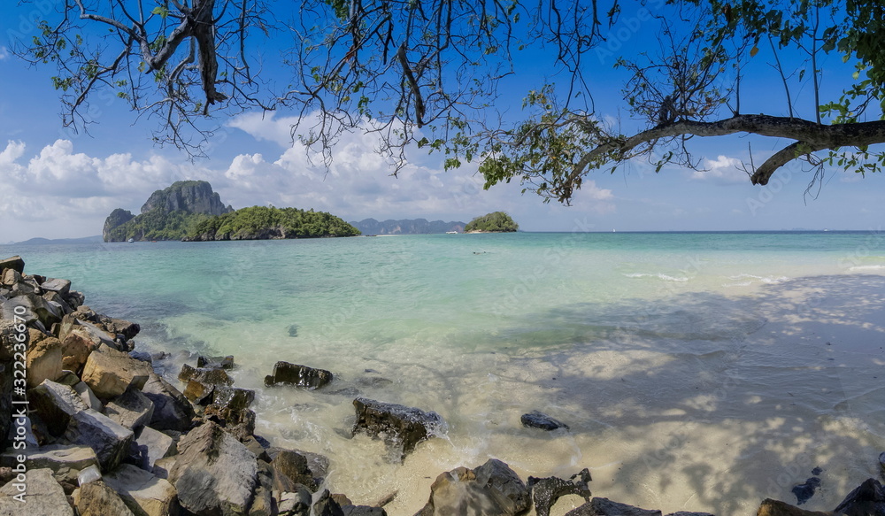 view of many arch rocks floating in blue-green sea with green island ...