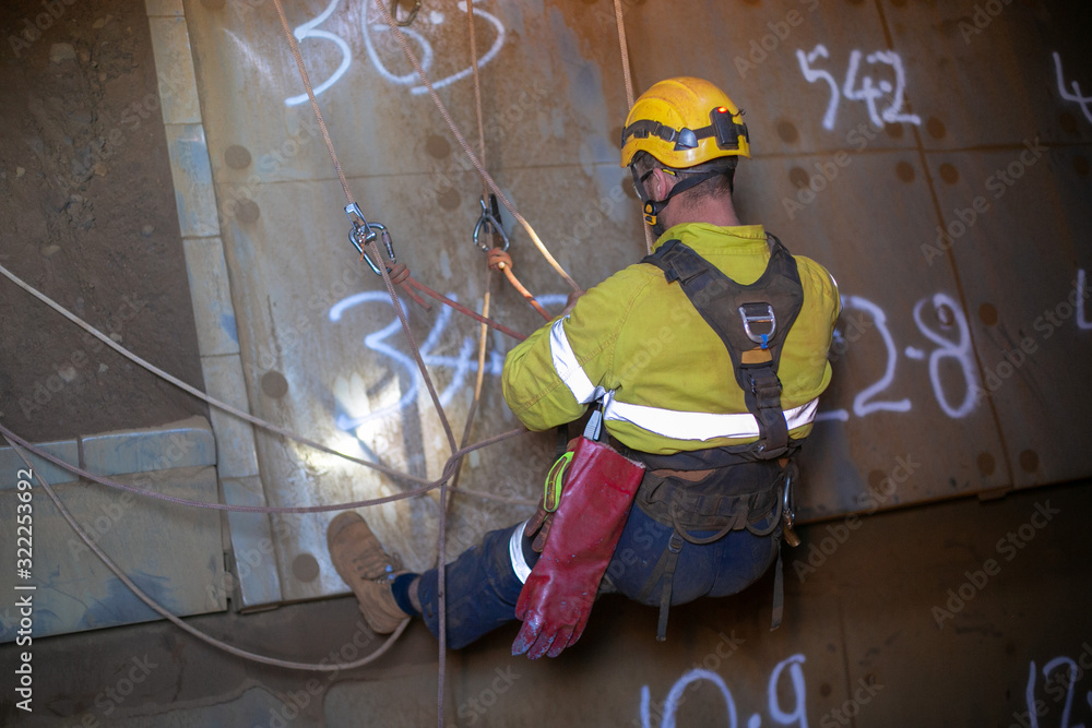 Industrial abseiler wearing full body safety equipment harness ...