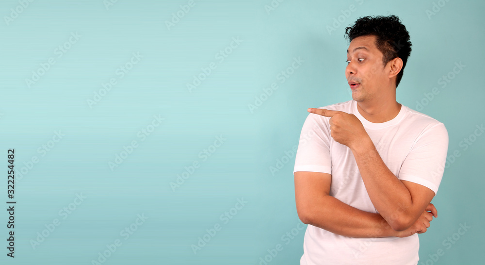 Shock and surprise face of asian man point on empty space on a blue ...