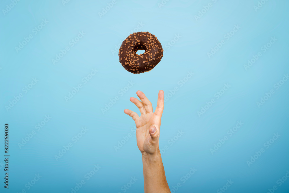 Hand catch a donut with chocolate icing. Blue cardboard background ...