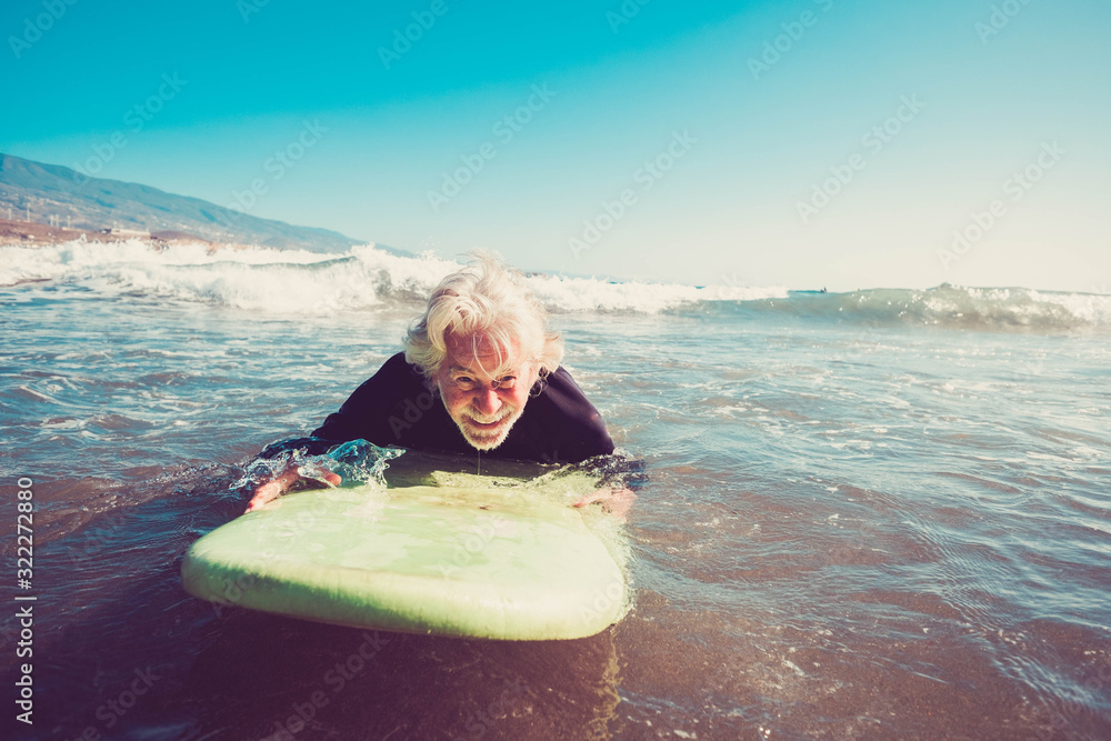 one senior trying surfing alone in the water of the beach and learning ...