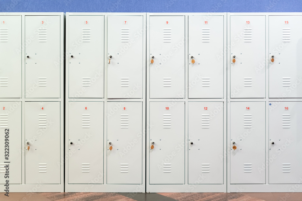 A row of grey metal school lockers with keys in the doors. Storage ...