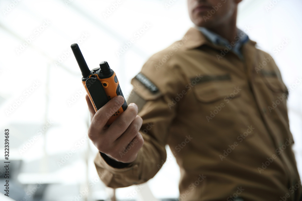 Professional security guard with portable radio set indoors, closeup ...