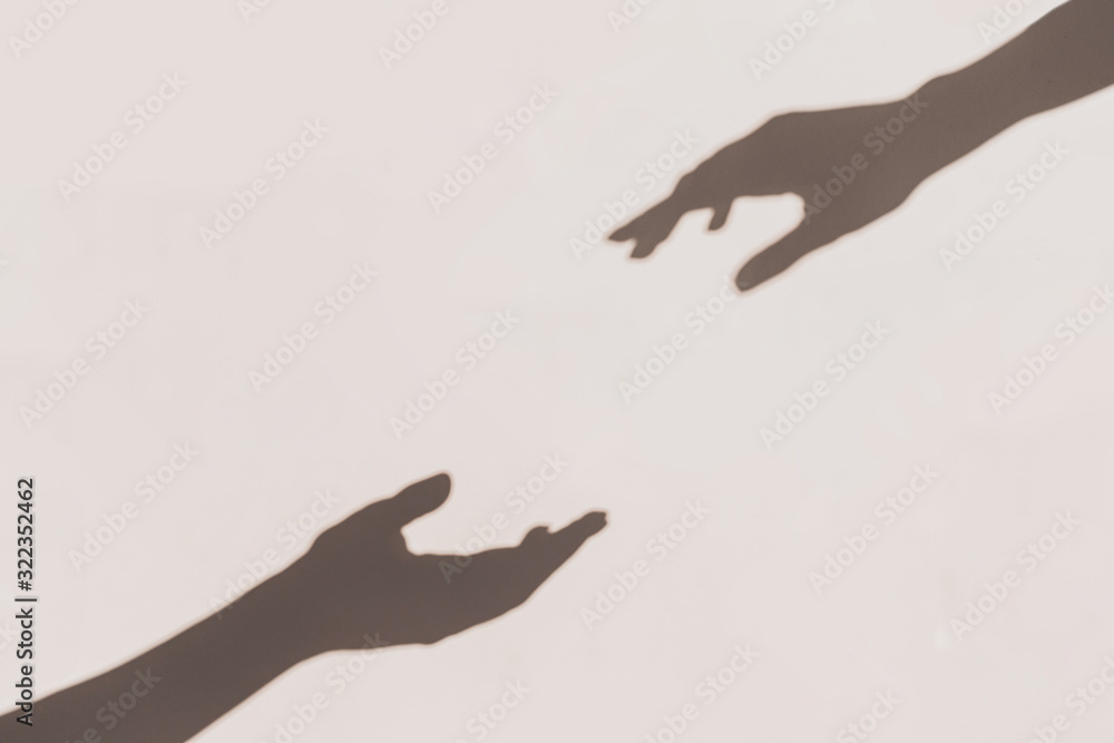 Grey shadows of hands reaching each other on the wall. Abstract blurred ...