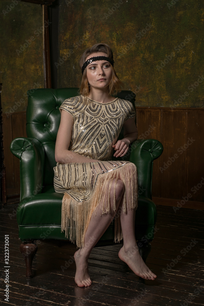 Portrait of young adult beautiful female model in 1920s style golden ...