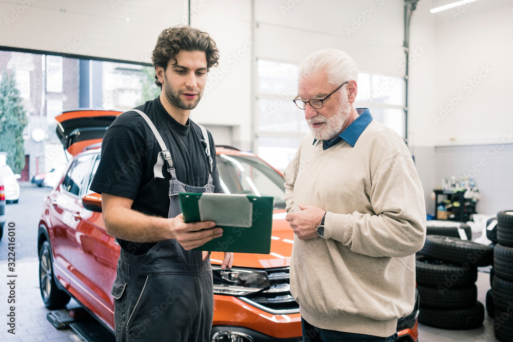 Car mechanic explaining check list to client in workshop Stock Photo ...